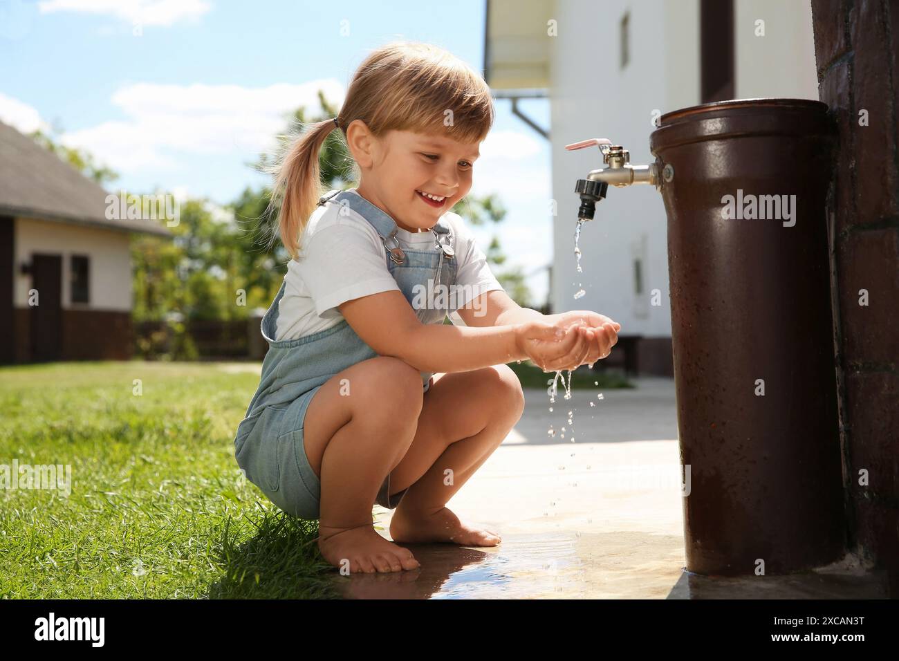 Water scarcity. Cute little girl drawing water with hands from tap ...
