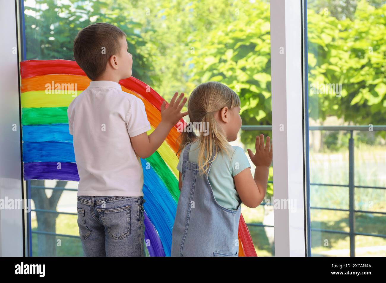 Children touching picture of rainbow on window indoors Stock Photo - Alamy