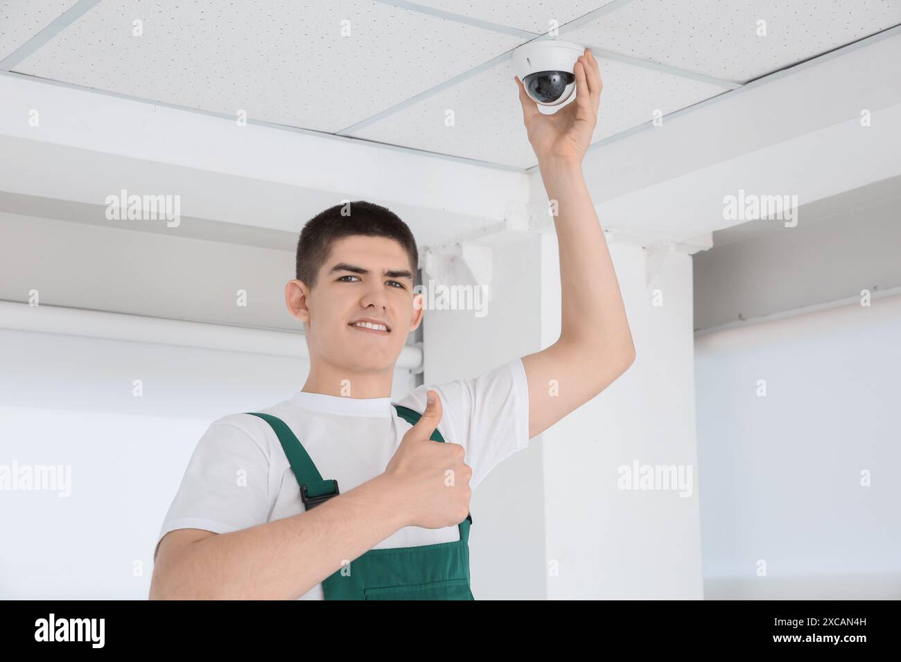 Technician showing thumbs up while installing CCTV camera on ceiling ...