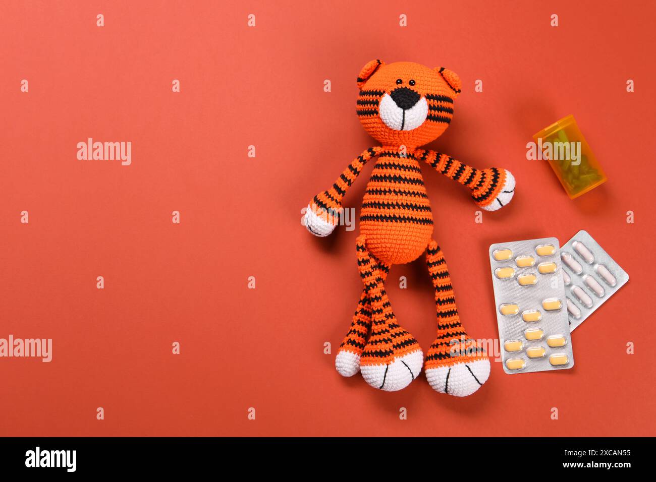 Toy tiger and pills on orange background, flat lay. Space for text ...
