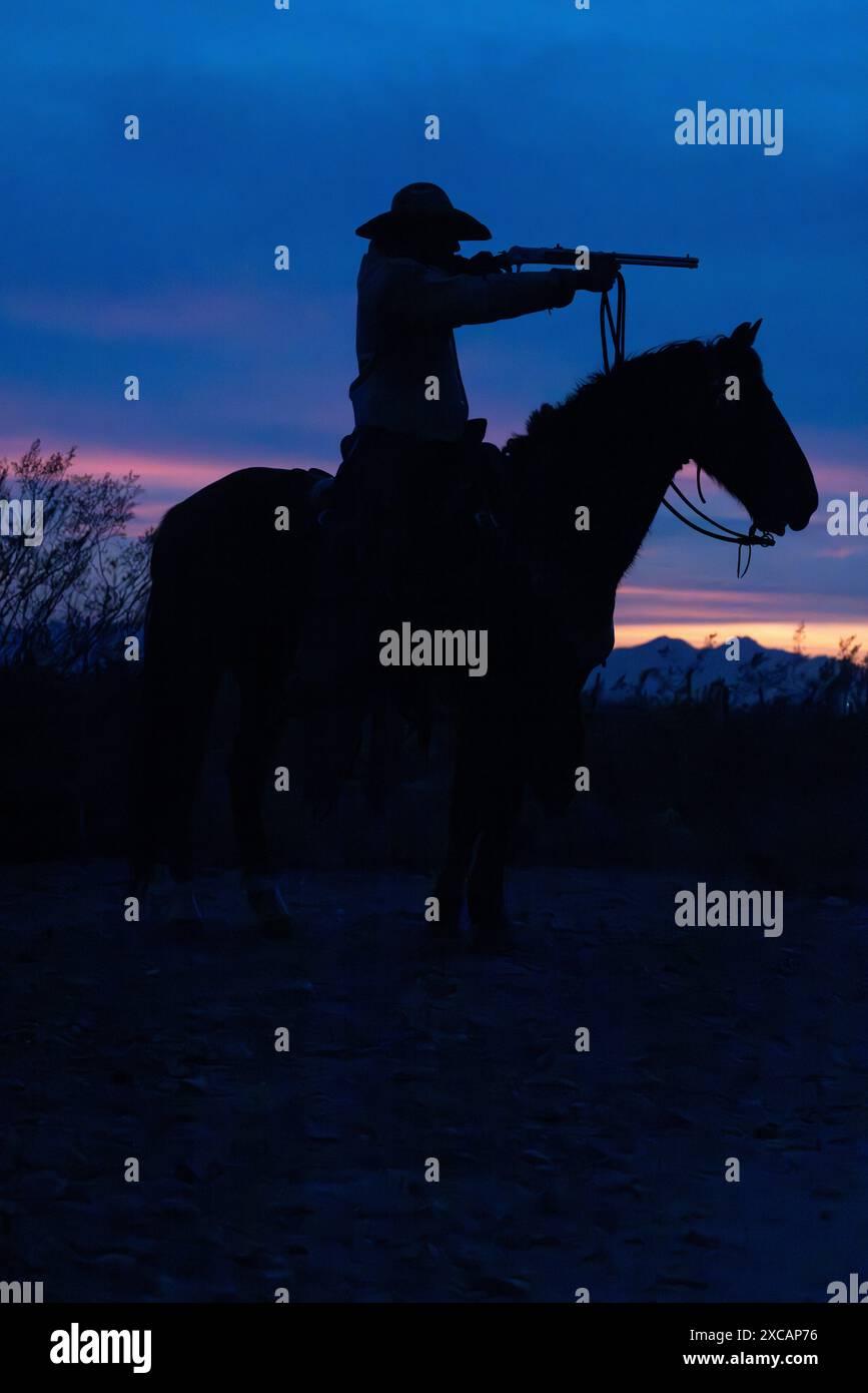 Silhouette of ranch hand, or cowboy, riding his horse in the sunset ...