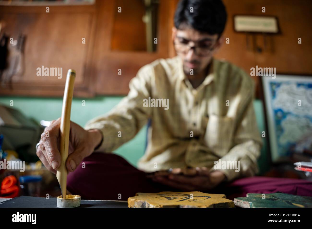 A calligrapher uses a tipped brush to create handwritten designs on ...