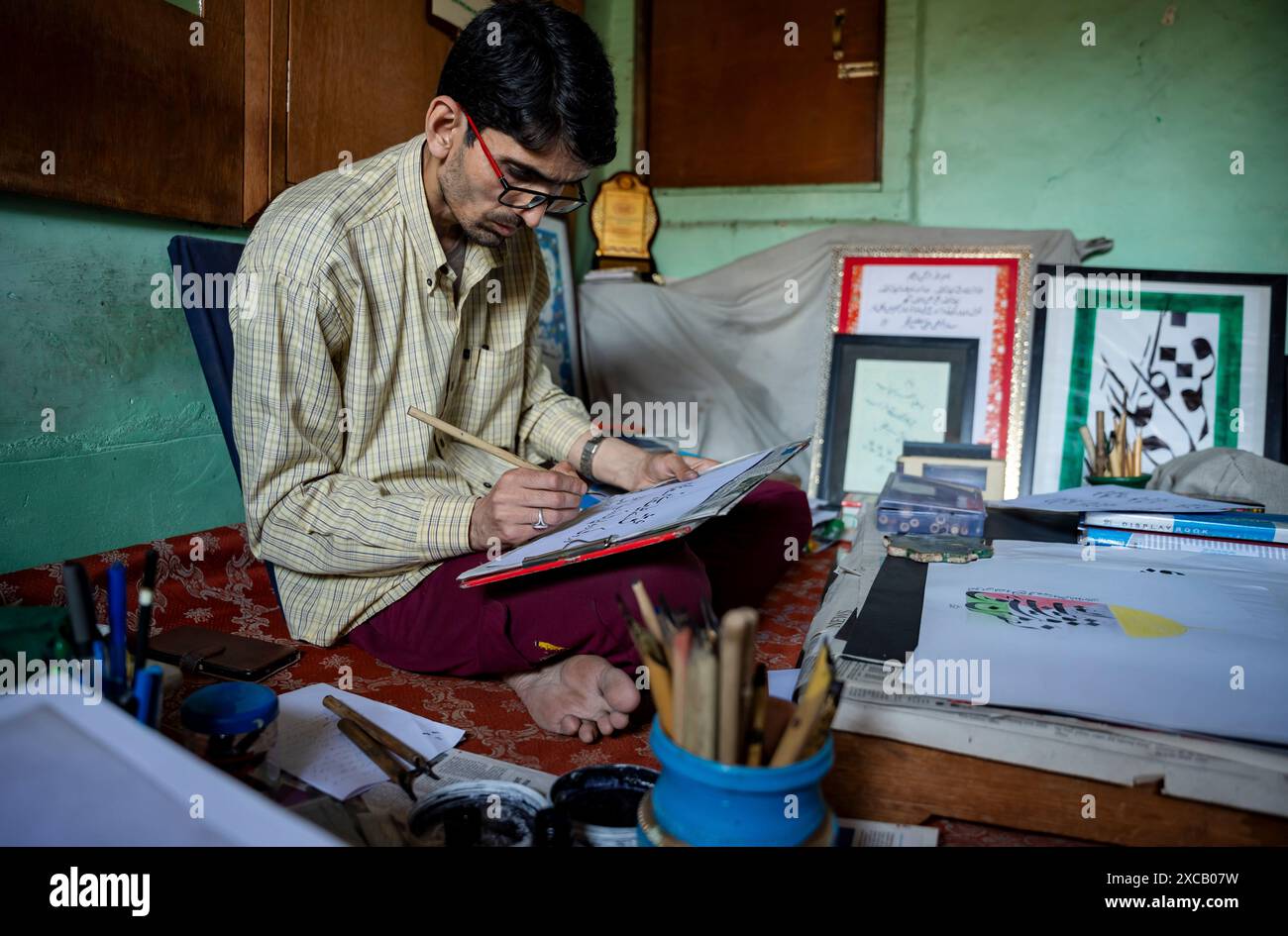 A calligrapher uses a tipped wooden brush to create handwritten designs ...