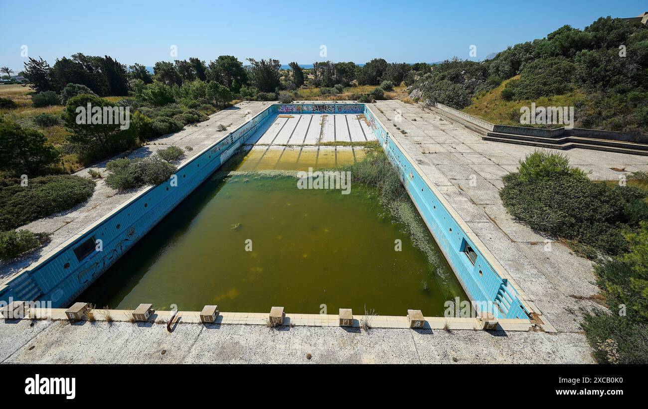 Abandoned swimming pool with algae-infested water, graffiti and ...