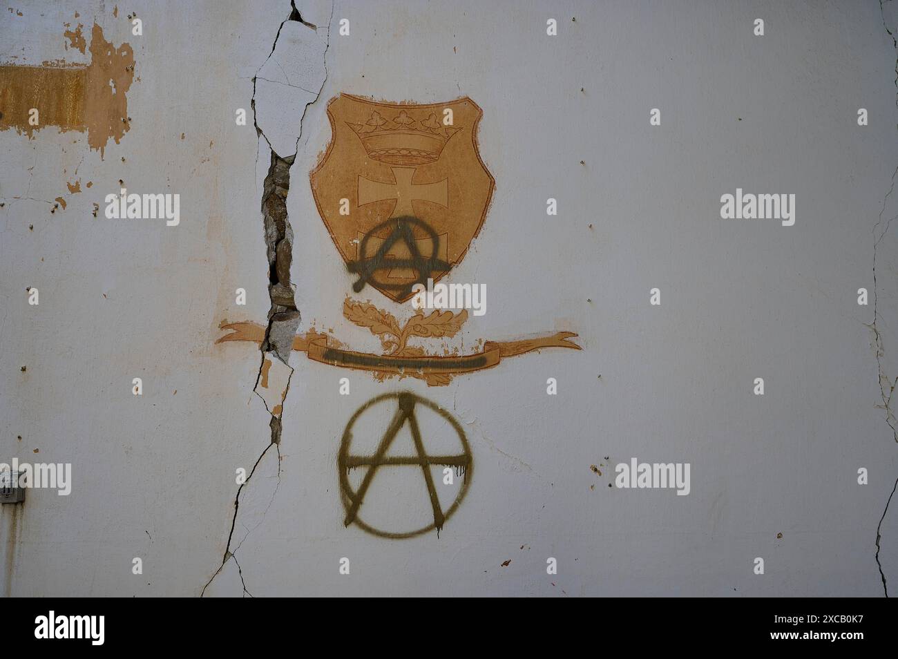 On a cracked white wall in an abandoned building, coats of arms and ...