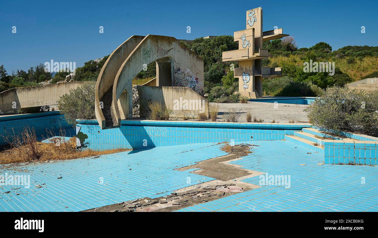 Abandoned swimming pool with concrete ruins and graffiti, surrounded by ...