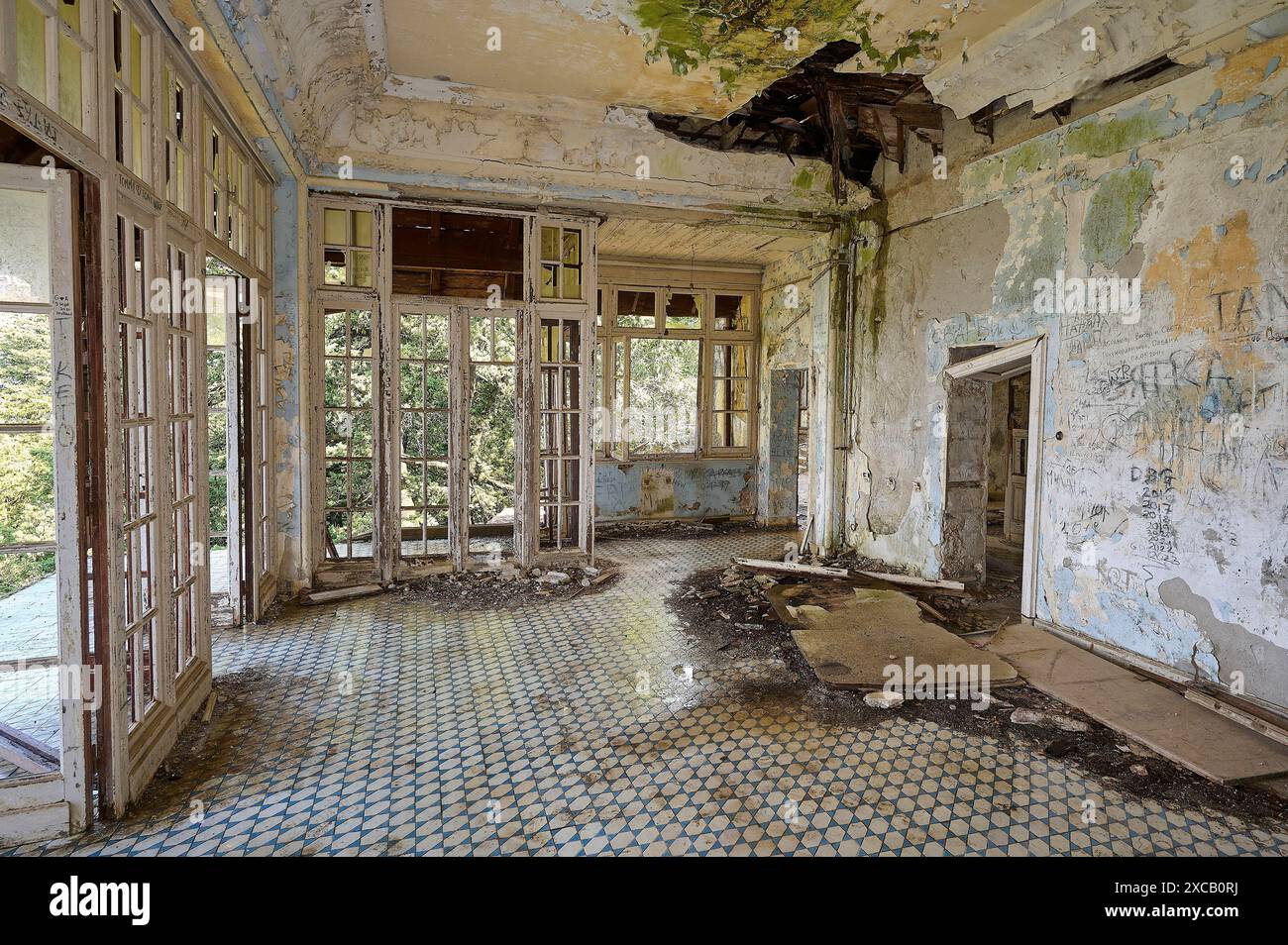 Dilapidated room with broken roof, damaged walls and graffiti, flooded ...