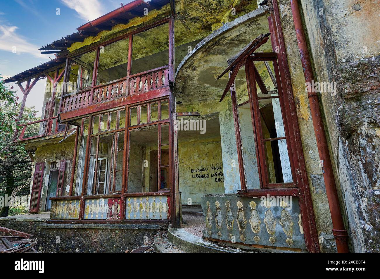 Sky replaced, Abandoned, dilapidated building with red doors and rusty ...