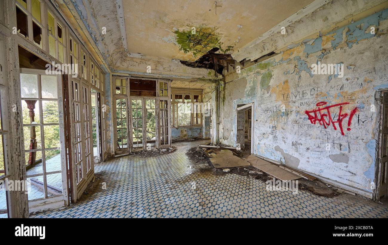 Abandoned room with broken roof, graffiti on the walls and light coming ...