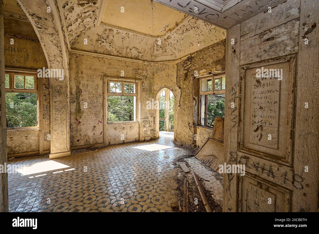 An abandoned room with decorated tiles, an arched entrance and open ...