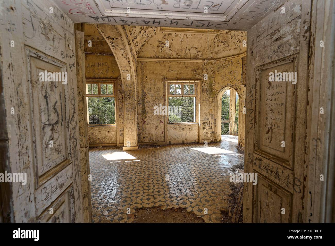 Dilapidated room with decorated tiles, open windows and arched doorway ...