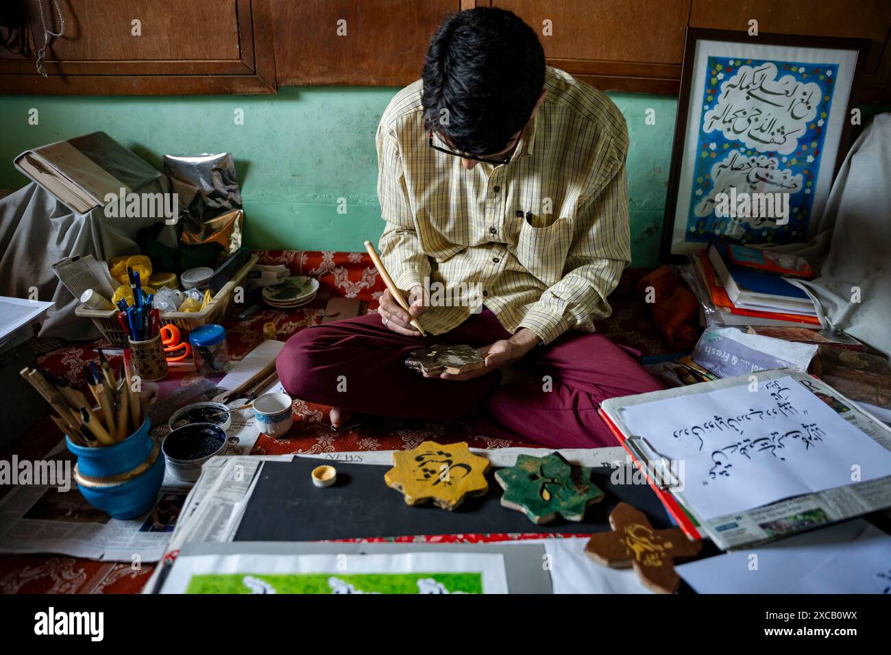 A calligrapher uses a tipped brush to create handwritten designs on dry ...