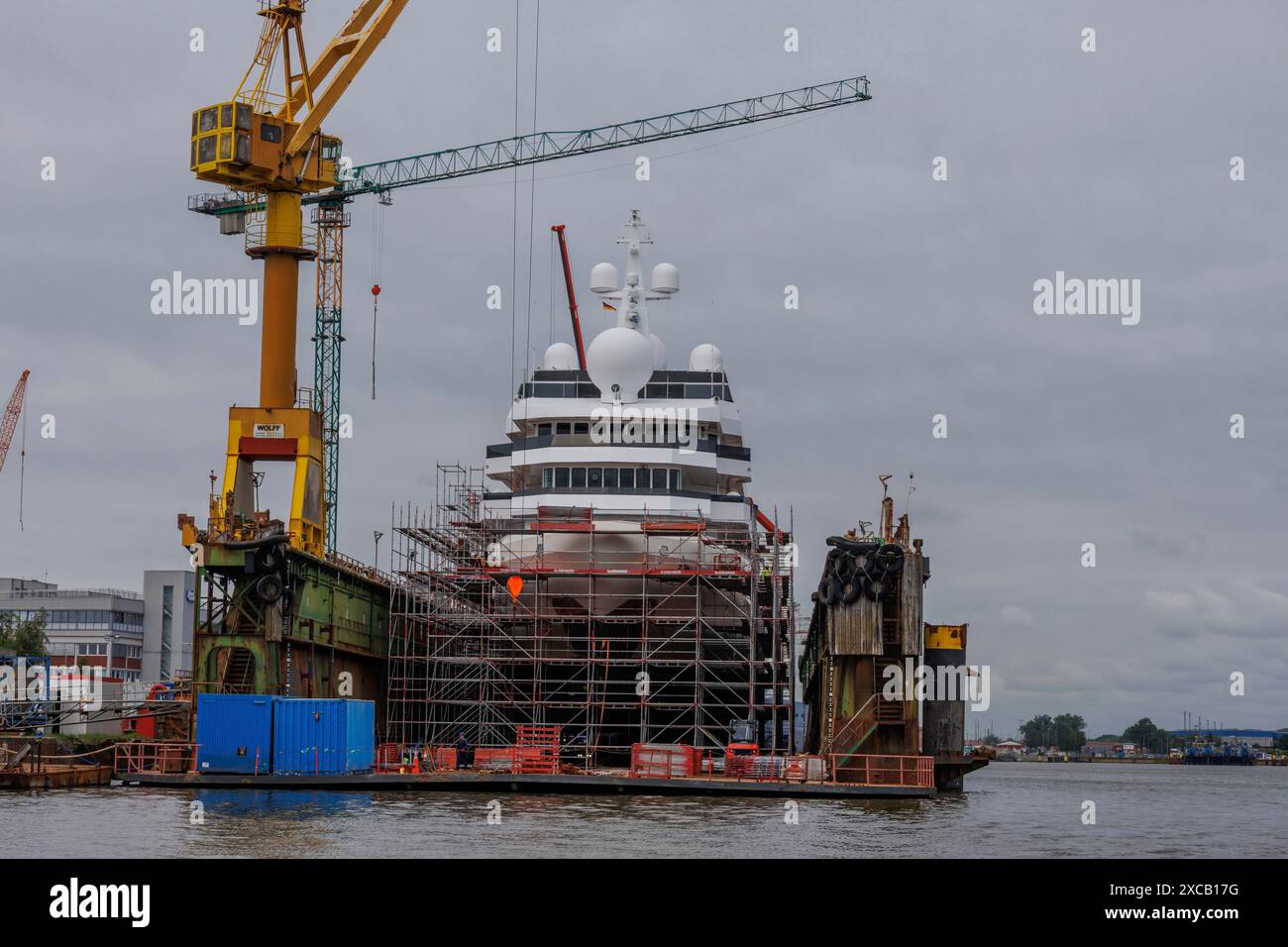 A large ship being repaired or rebuilt in a shipyard, surrounded by ...