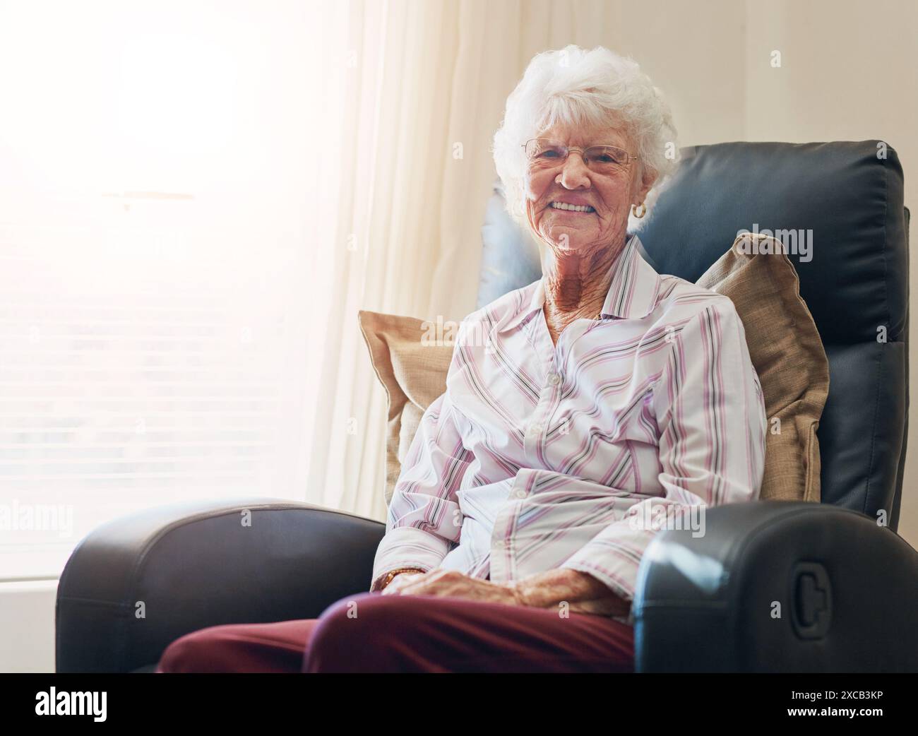 Happy, portrait and senior woman relax on a chair in nursing home with ...