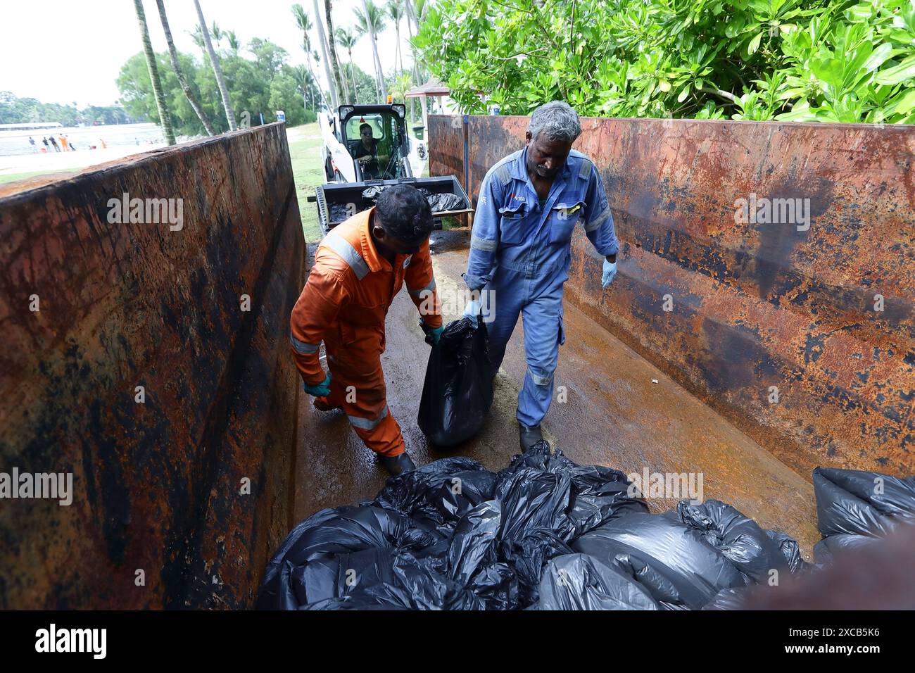 Workers load bags of oil-stained sands at Sentosa's Tanjong Beach area ...
