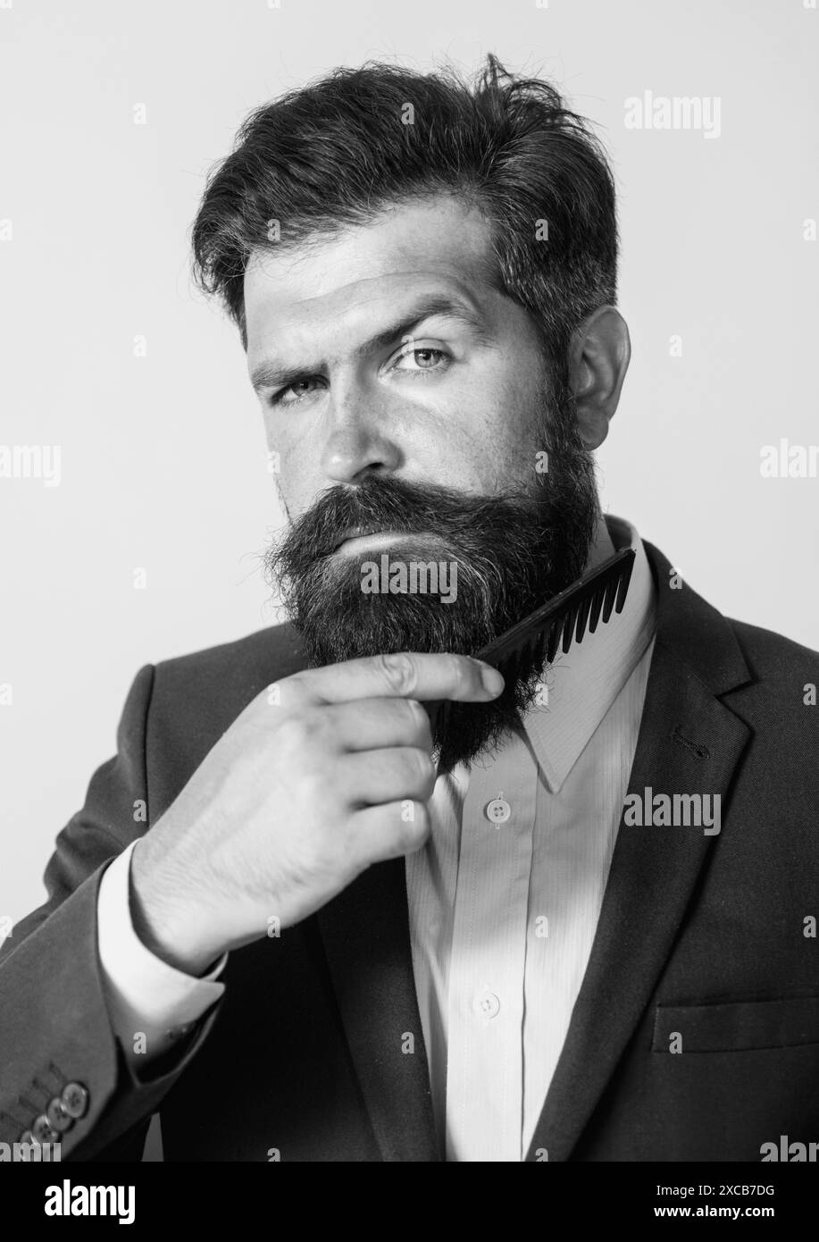 Bearded man combing beard. Close up of a young man styling his long ...