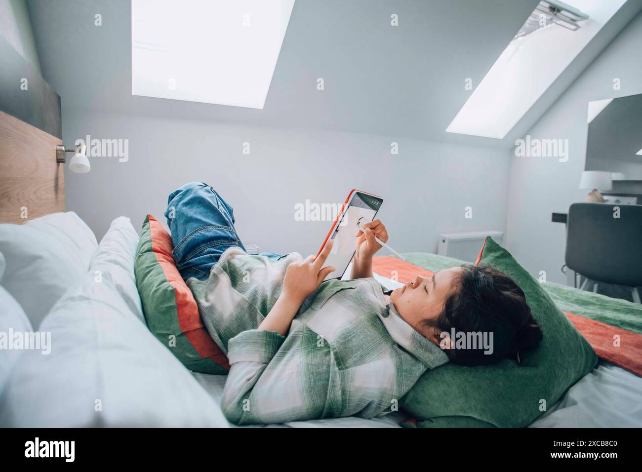 In the quiet comfort of her bedroom, girl uses her tablet to sketch, finding solace and ...