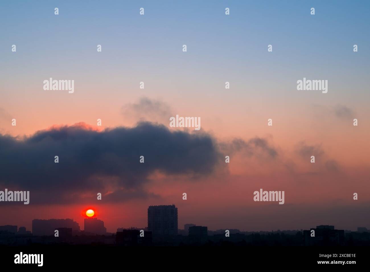 Dawn. Heavy cloud in the morning sky over the city. Silhouettes of ...