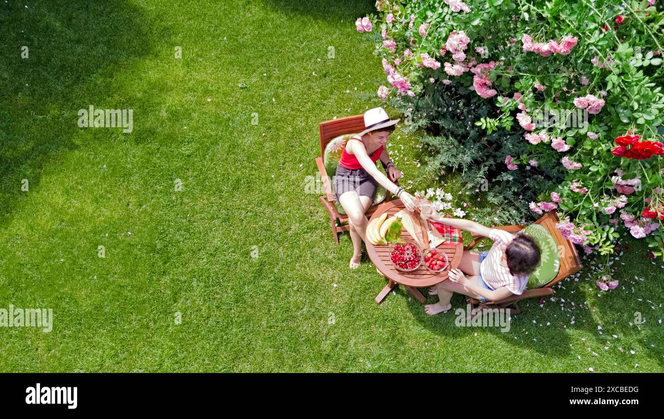 Friends eating together outdoors in summer garden, girls have picnic in ...