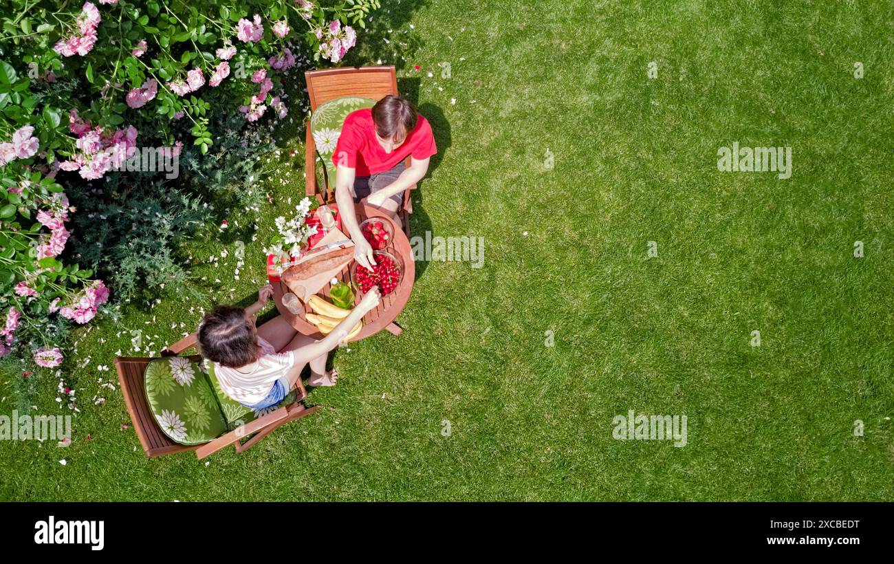 Young couple enjoying food and drinks in beautiful roses garden on ...