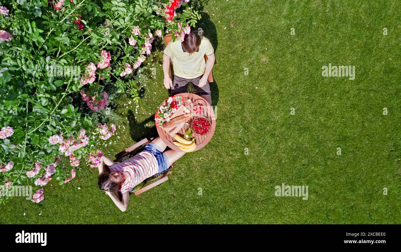 Young couple enjoying food and drinks in beautiful roses garden on ...