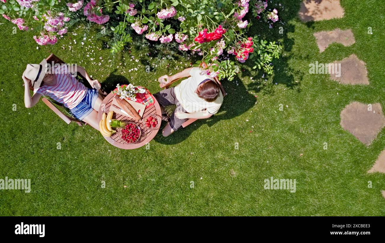 Young couple enjoying food and drinks in beautiful roses garden on ...
