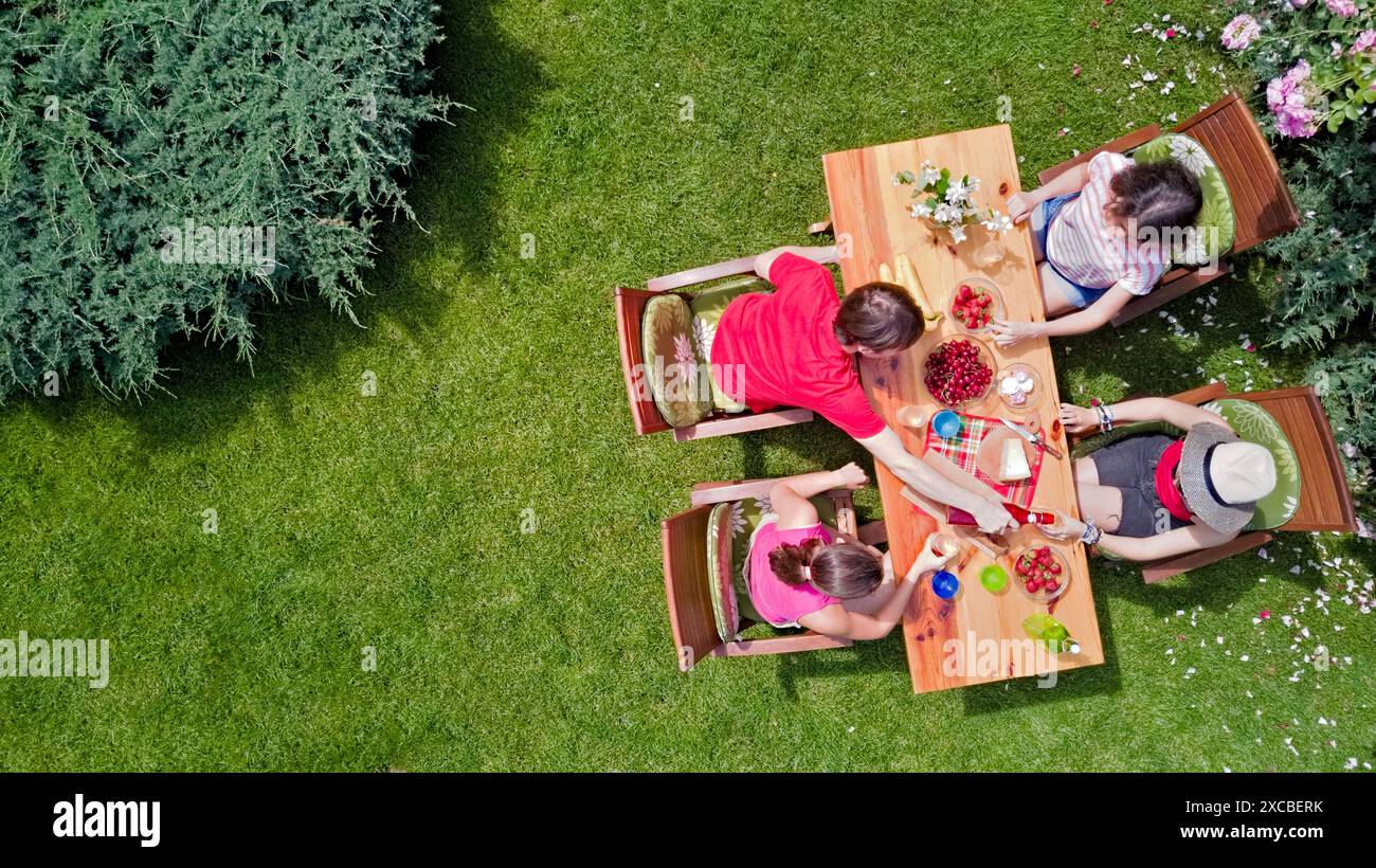 Family and friends eating together outdoors on summer garden party ...