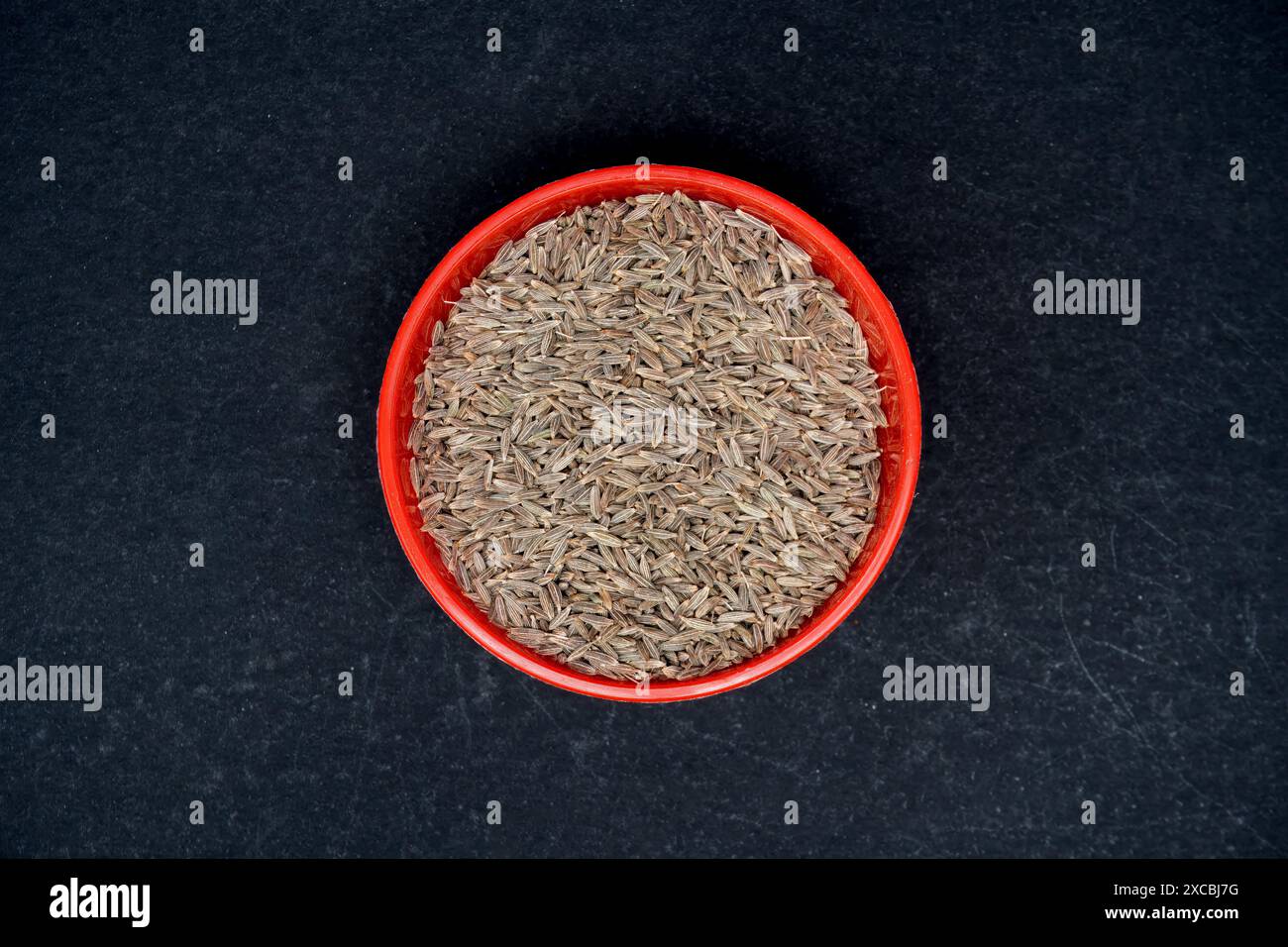top view of Cumin seeds in red bowl isolated on black background Stock ...