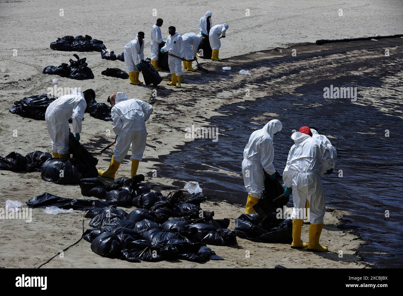 Workers clean oil spill along Sentosa's Tanjong Beach area in Singapore ...
