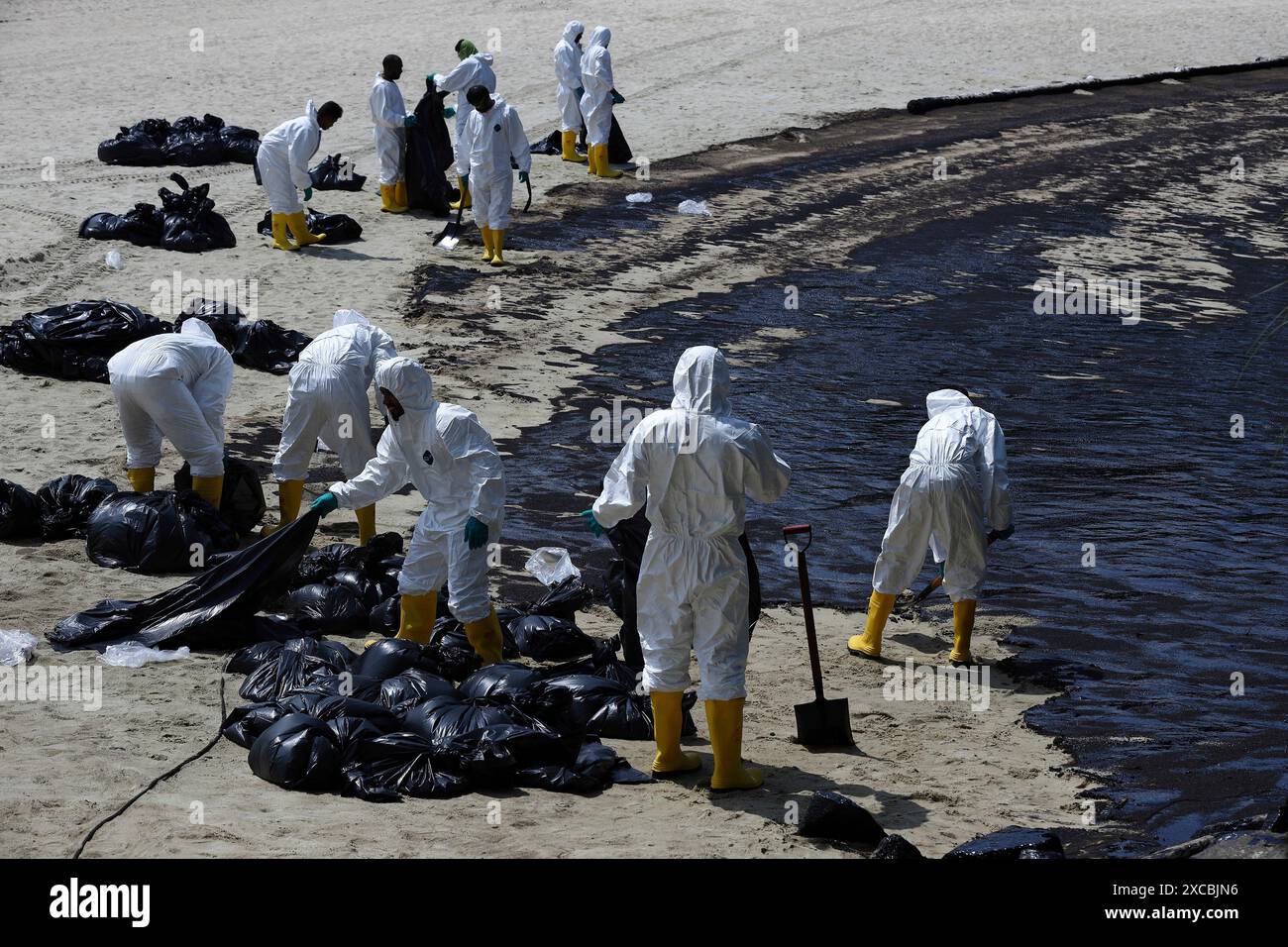 Workers clean oil spill along Sentosa's Tanjong Beach area in Singapore ...