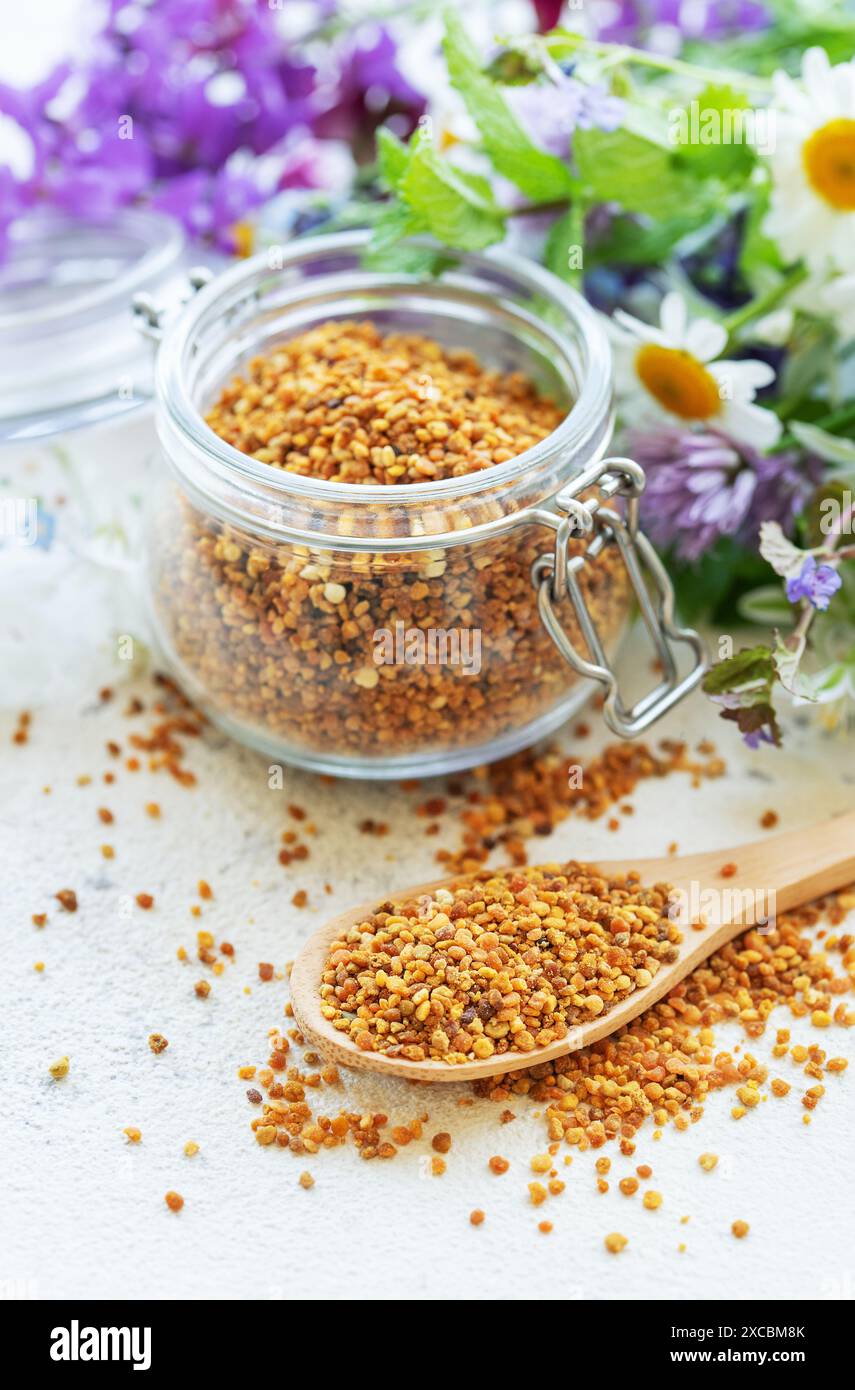 Healthy bee pollen grains. Bee pollen on a glass jar and wild flowers ...