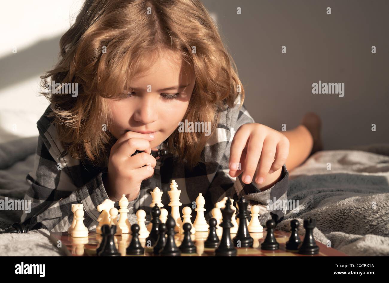 Child playing chess on bed. Thinking child. Chess game for kids ...