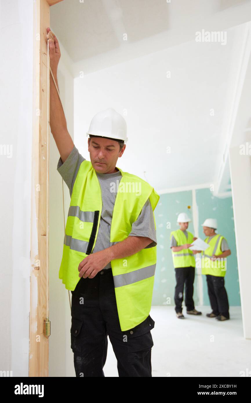 Worker with protective equipment, PPE, Checking and aligning vertical ...