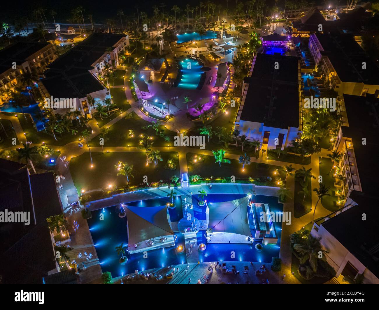 An Aerial night view of a luxurious resort with illuminated pools and ...