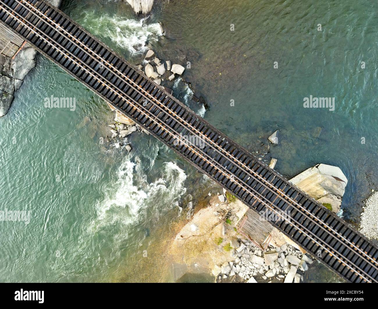 An Aerial view of a railway bridge crossing a river with clear water ...