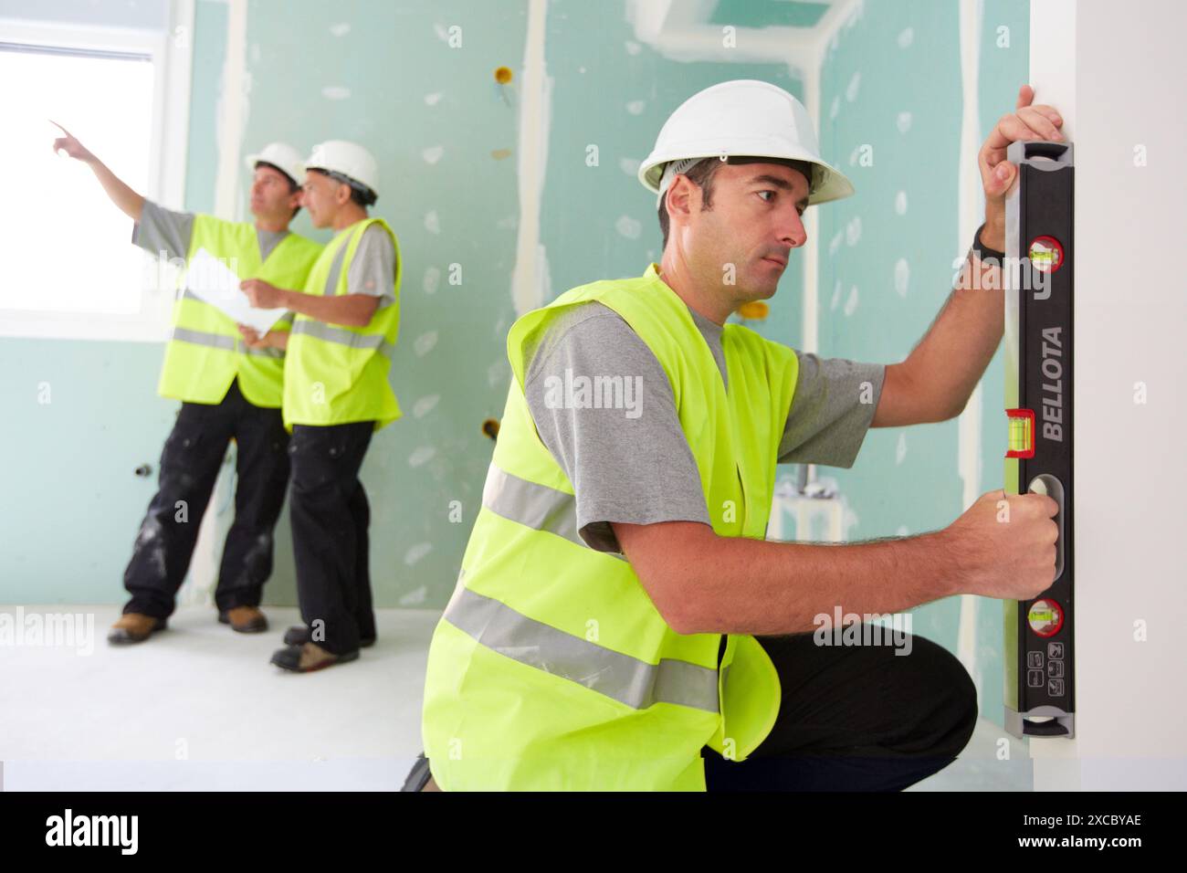 Worker with protective equipment, PPE, Leveling plasterboard panels ...