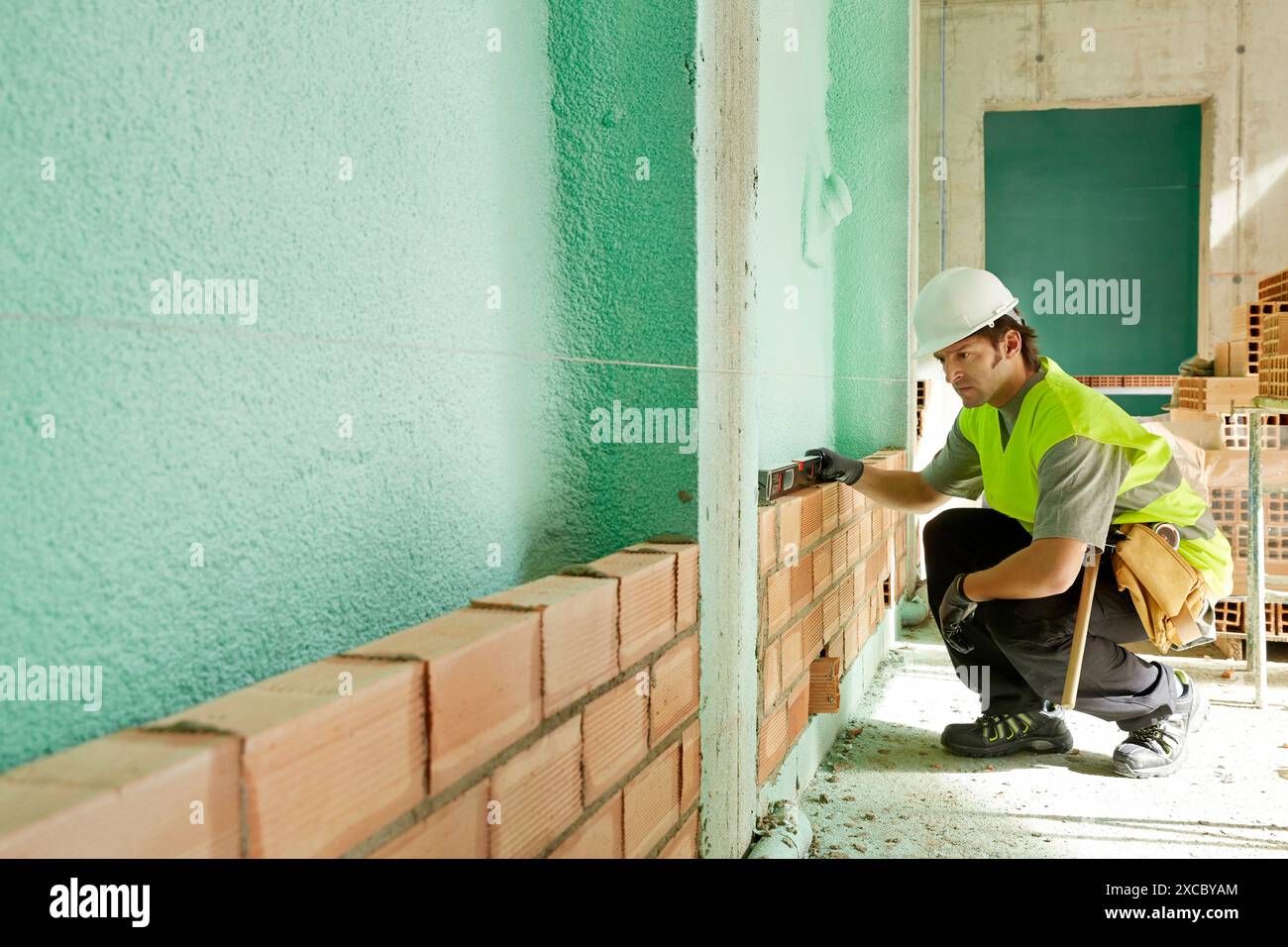 Mason checking the level of a brick wall, Bricklayer with personal ...
