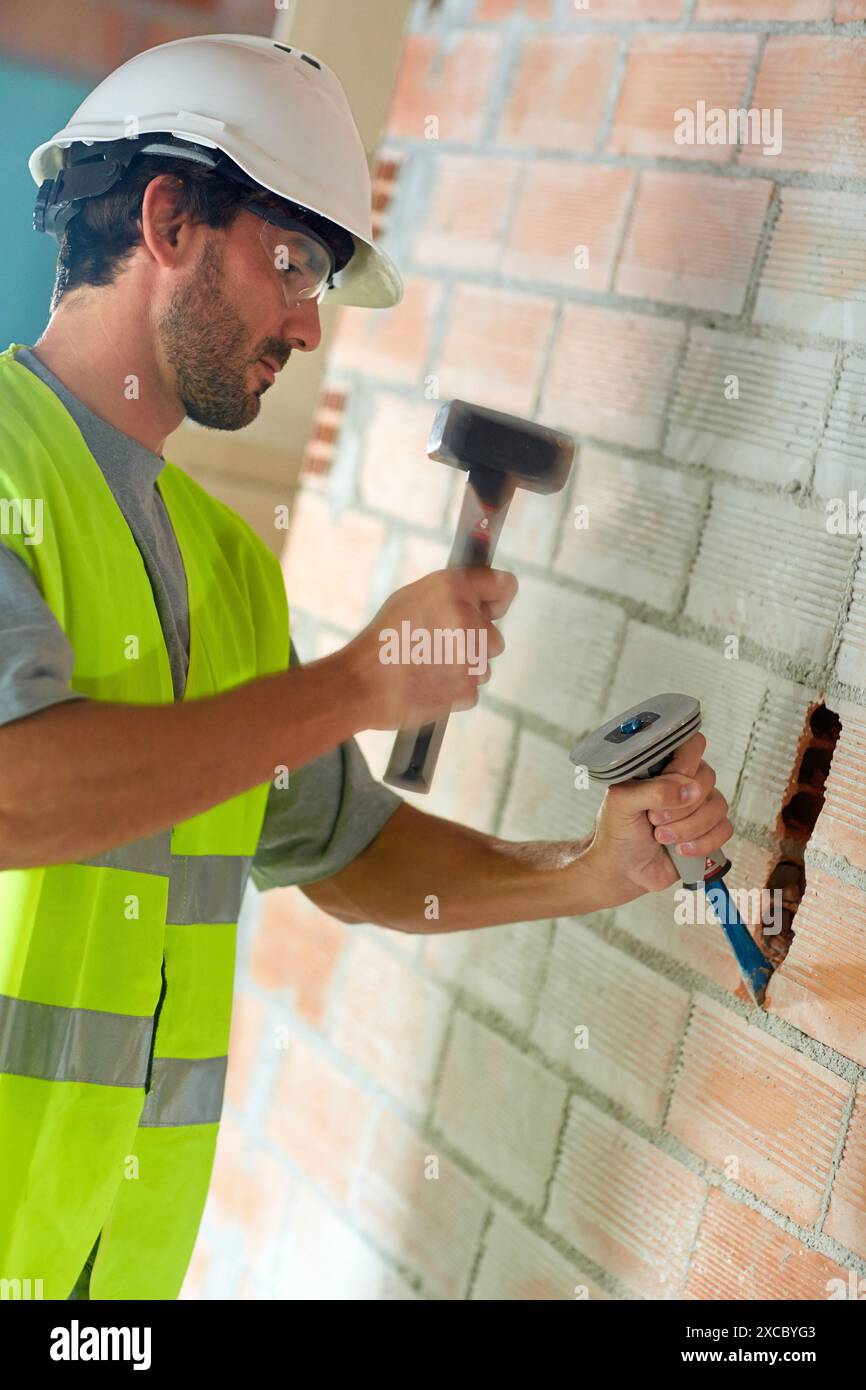 Bricklayer making a groove in the brick wall to place electrical wires ...