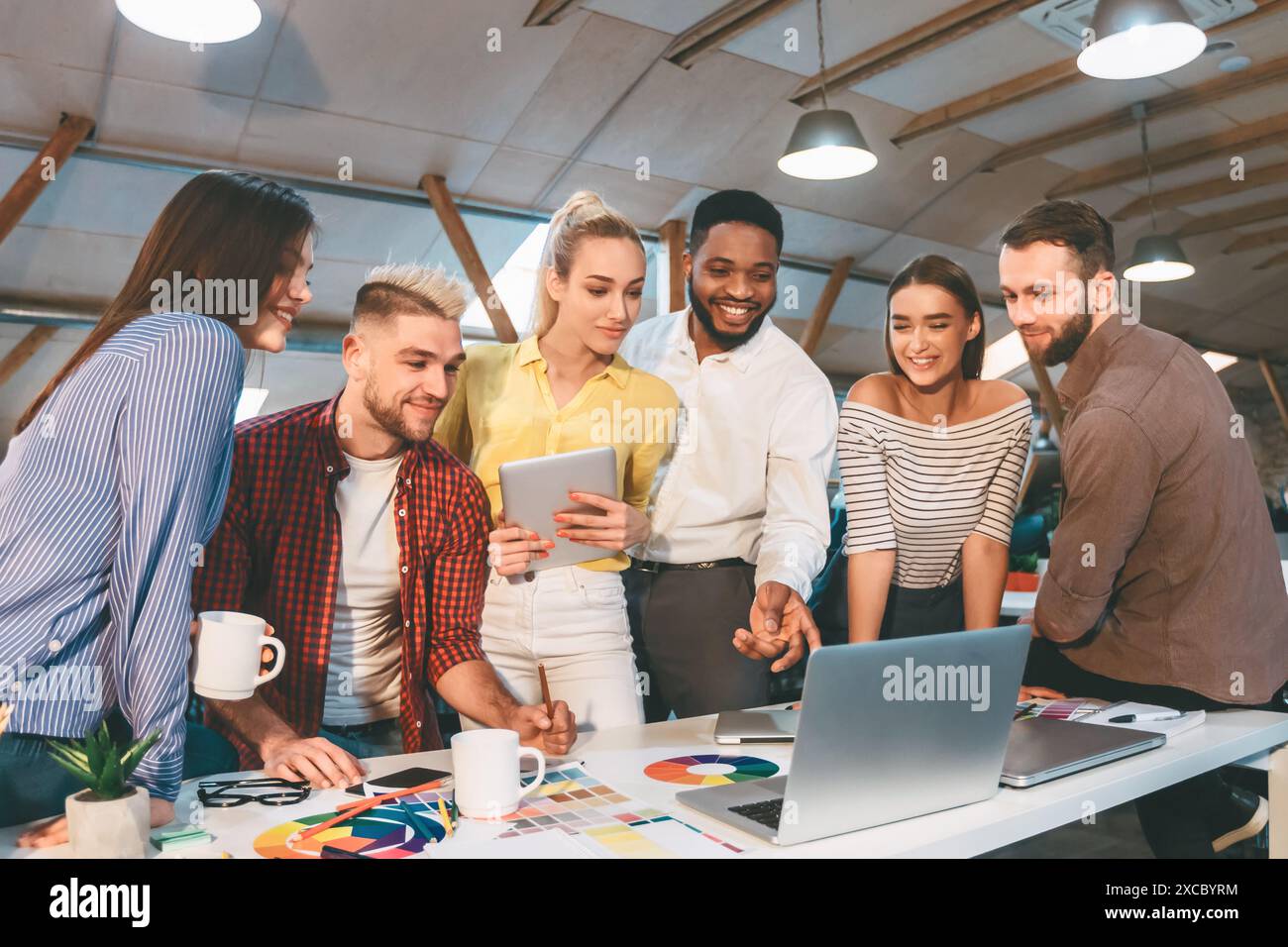 Group of People Standing Around Table With Laptop Stock Photo - Alamy