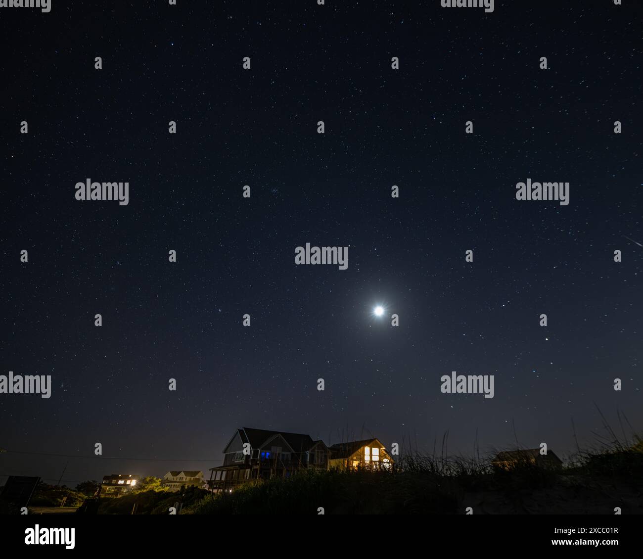 A serene night sky filled with stars over a quiet residential area with ...