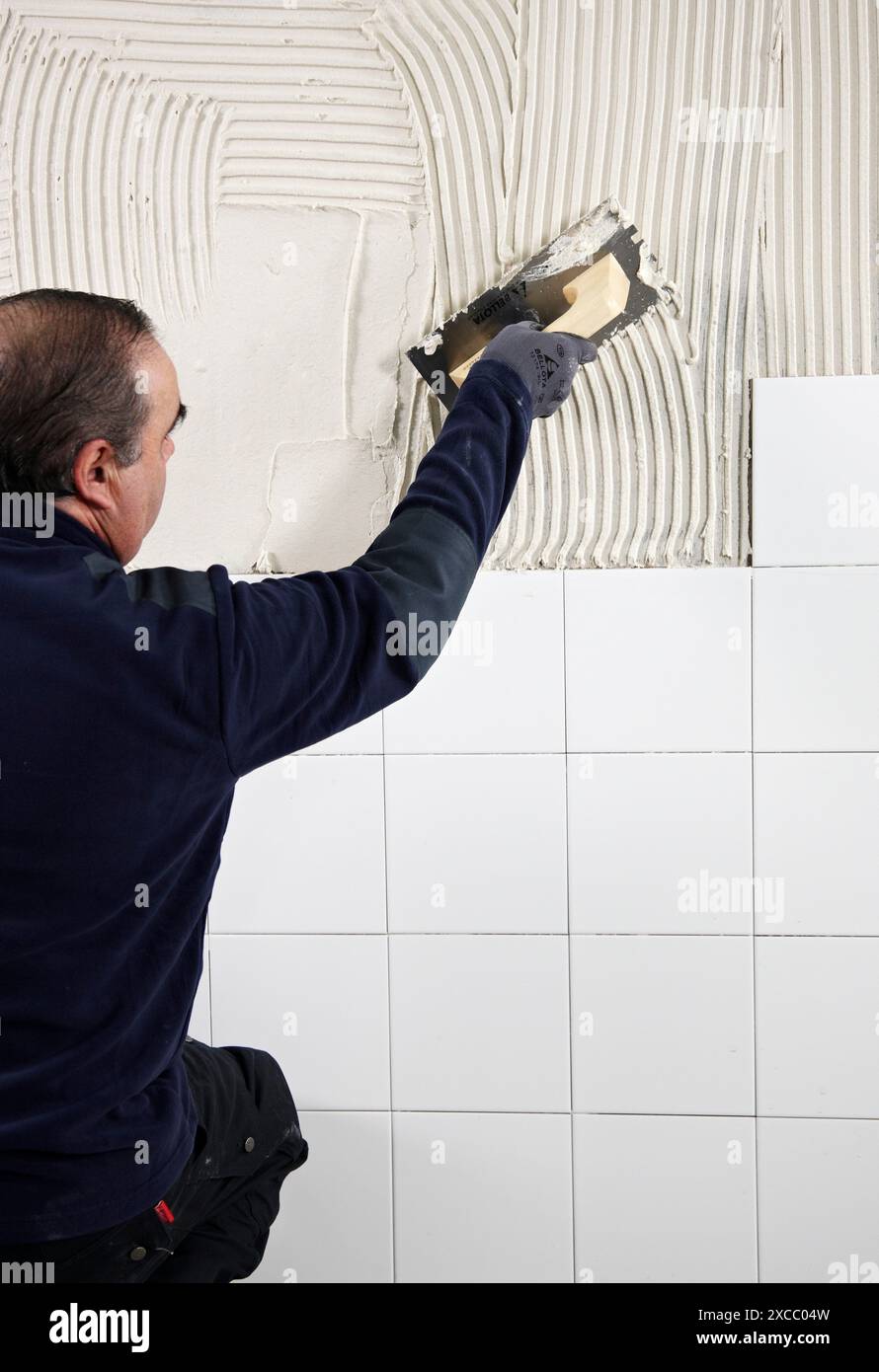 Preparing wall with glue mortar before tiling using a serrated ...