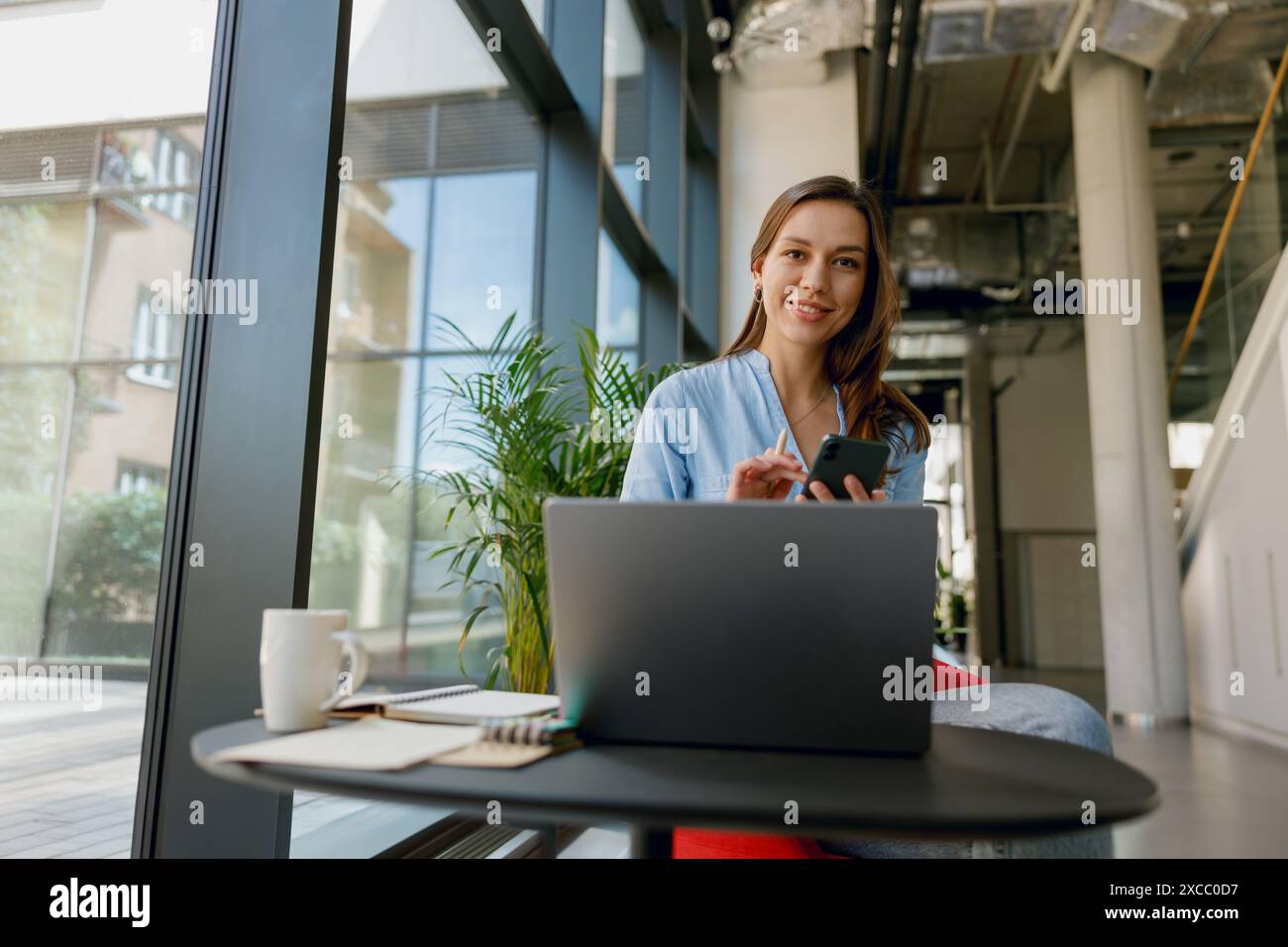 Woman in modern office, using laptop and smartphone, showing ...