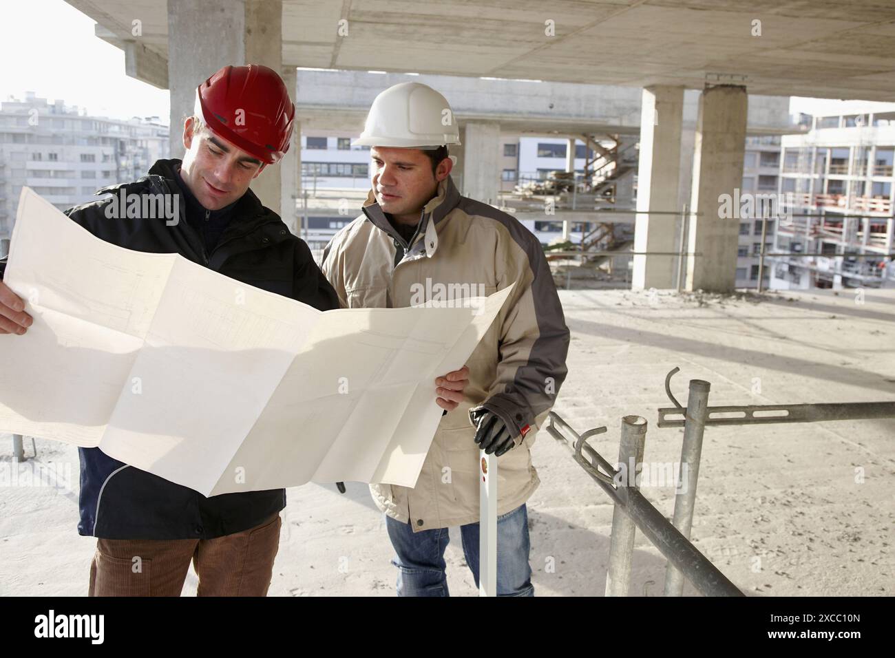 Architect and construction worker looking at blueprints, personal ...