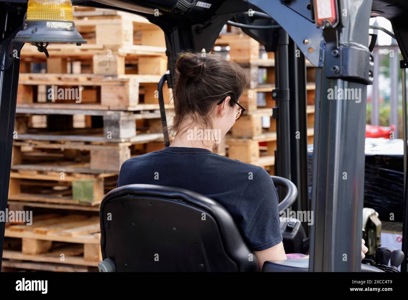 Young woman operating a forklift in a warehouse with wooden pallets in ...