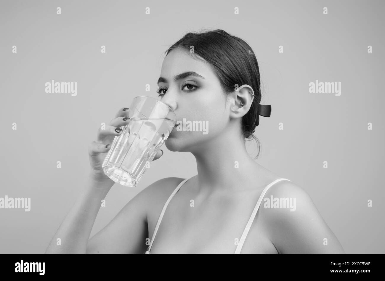 Woman drinking water, isolated on studio background. Portrait of happy ...