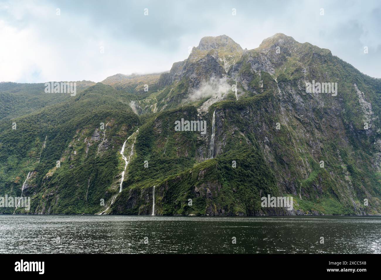 Sightseeing cruise with majestic mountain and waterfall flowing in ...
