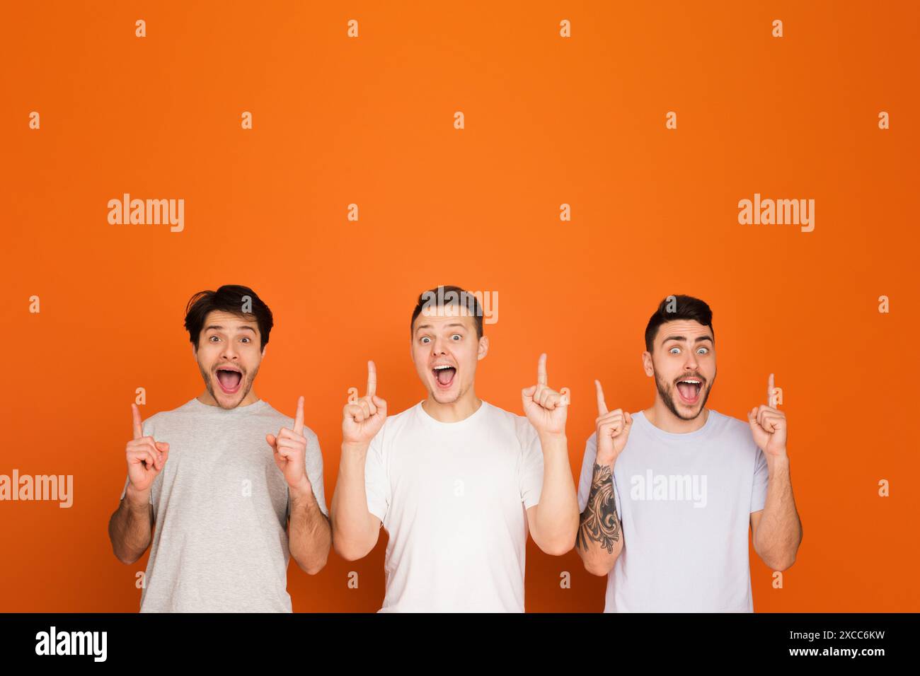 Three friends pointing upwards smilingly, copy space Stock Photo - Alamy