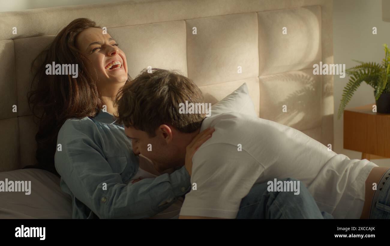 Man falling on bed woman couple female male tickling laughing bedroom ...