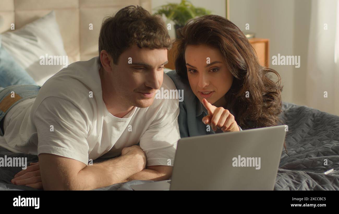 Two people couple man woman looking at laptop screen girlfriend show ...