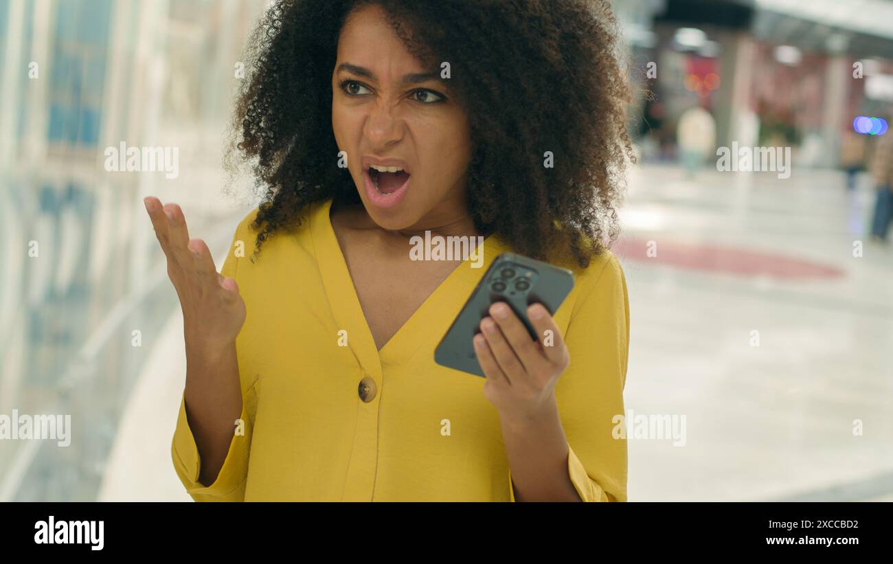 Angry African American woman holding mobile phone smartphone cellphone ...